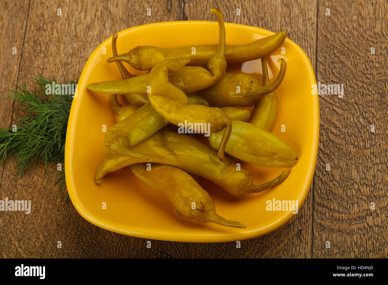 Pickled green pepperoni pepper in the bowl on wood background Stock ...