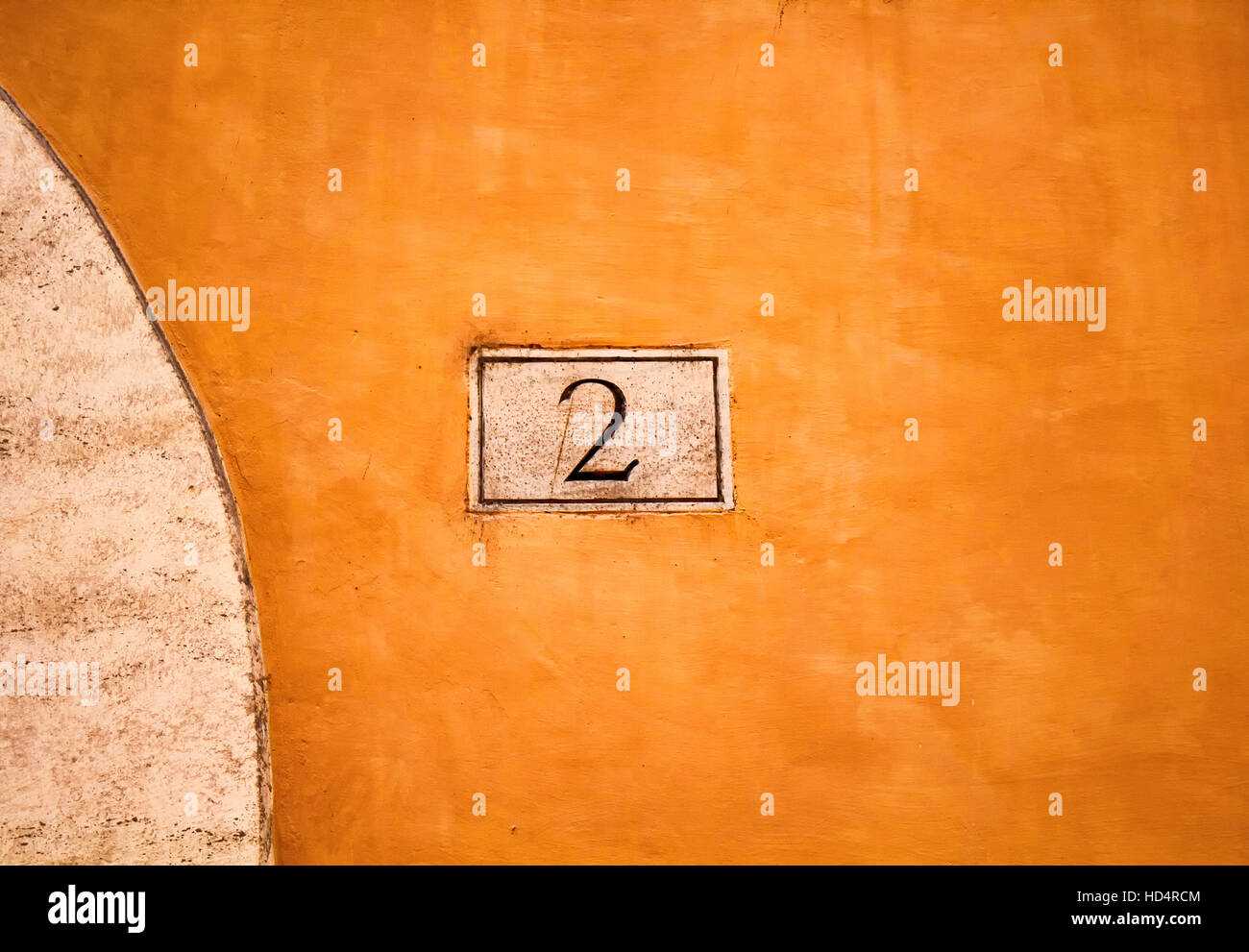Engraved building number (2) on orange colour, old wall in Rome Stock ...