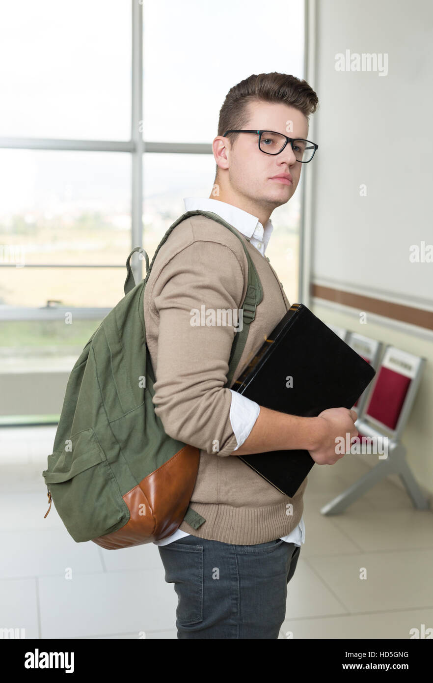 Portrait of acollege student carrying a backpack and standing in a ...