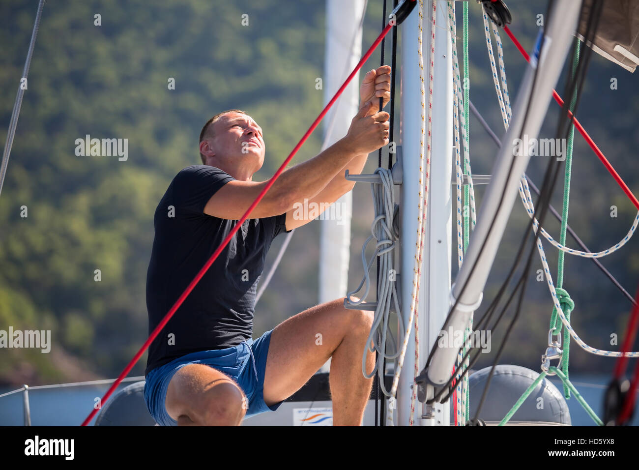 Yachtsman pulls the rope controlling the sail on sailing boat Stock ...