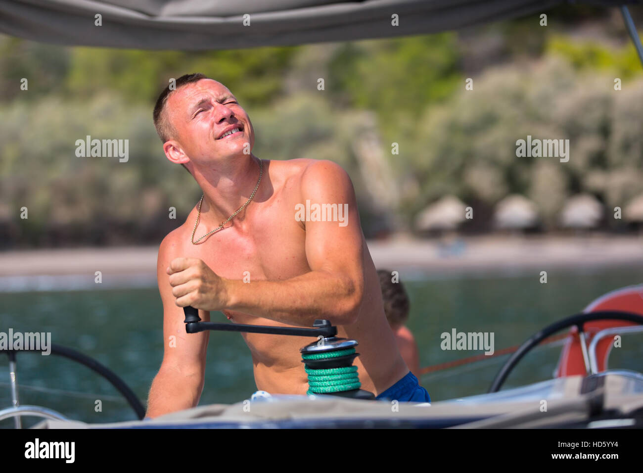Yachtsman turns winch rope controlling sail on sailing boat Stock Photo ...