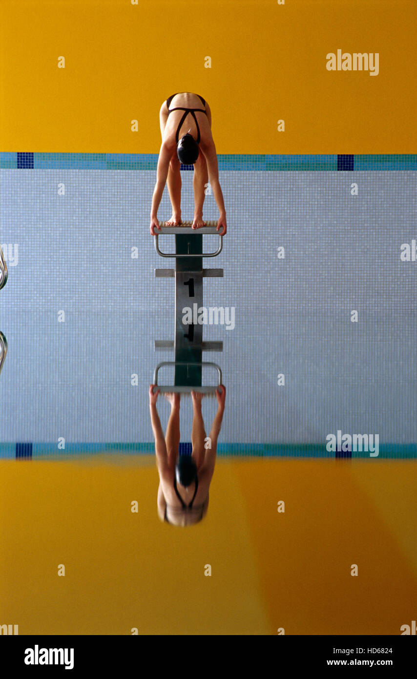 Swimmer about to dive from a starting block in an indoor pool with ...