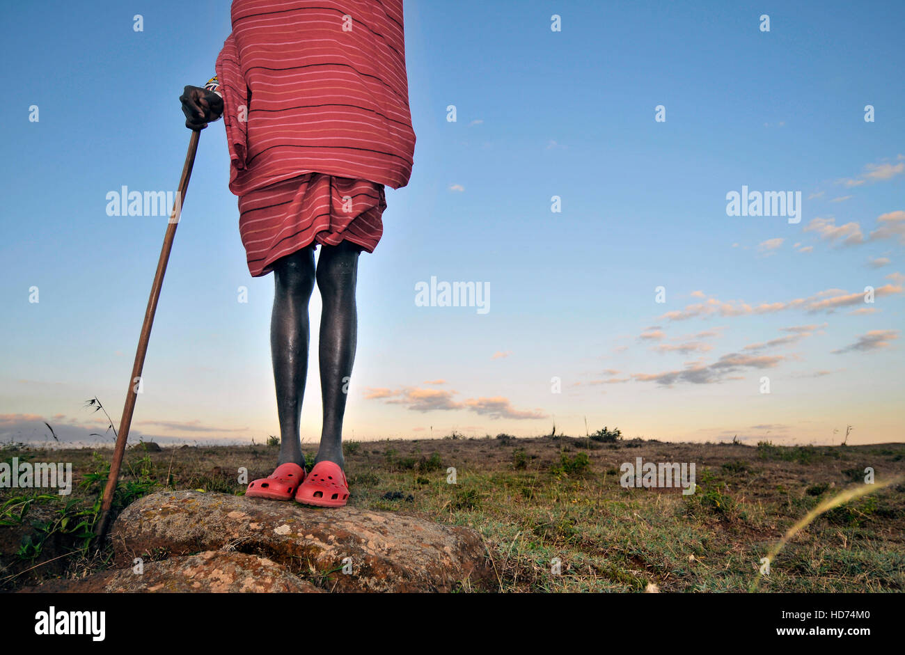 Maasai Warrior wearing traditional tribal clothing with Crocs. Blue sky ...