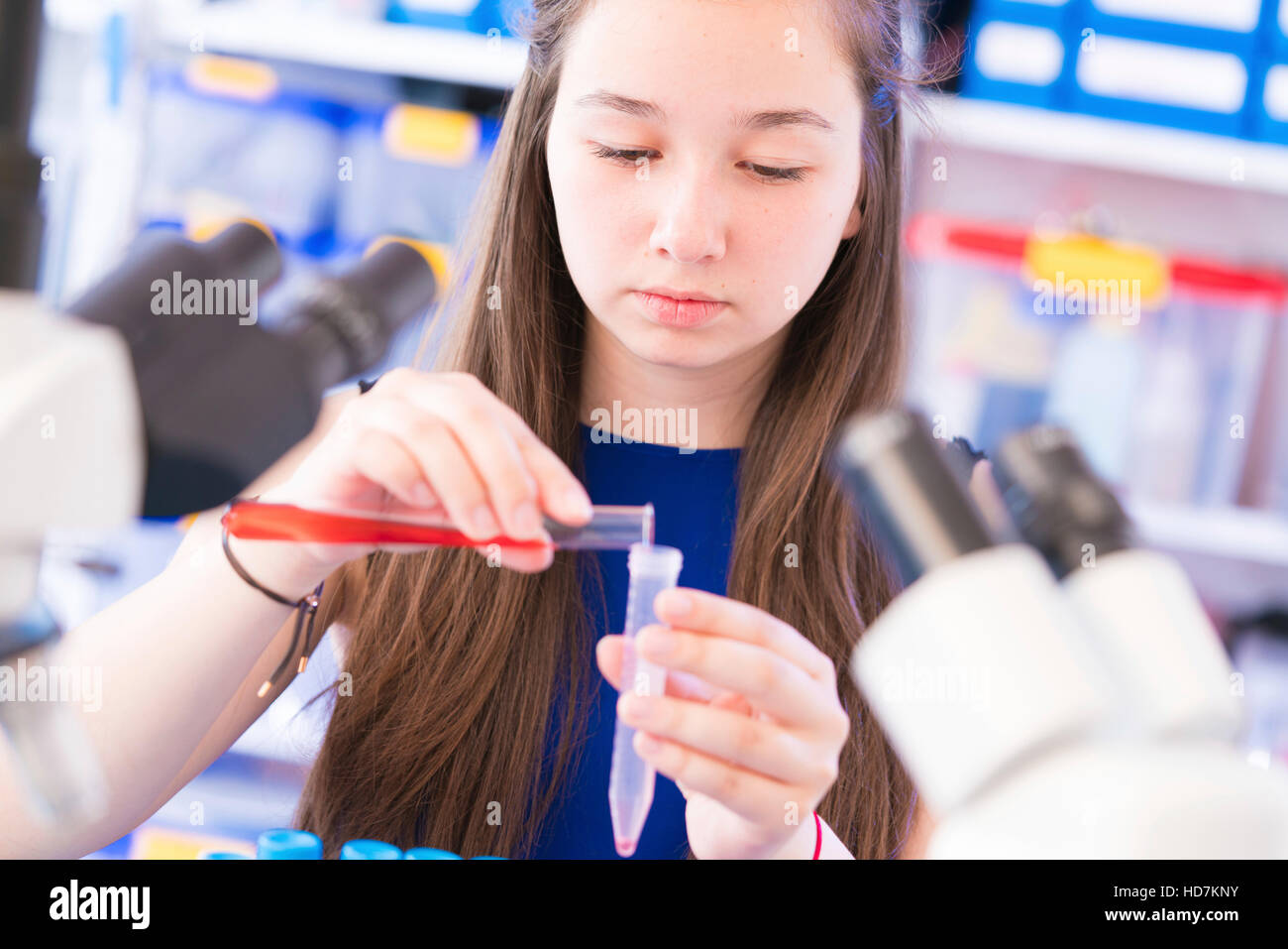 MODEL RELEASED. Girl pouring chemical into test tube in laboratory ...