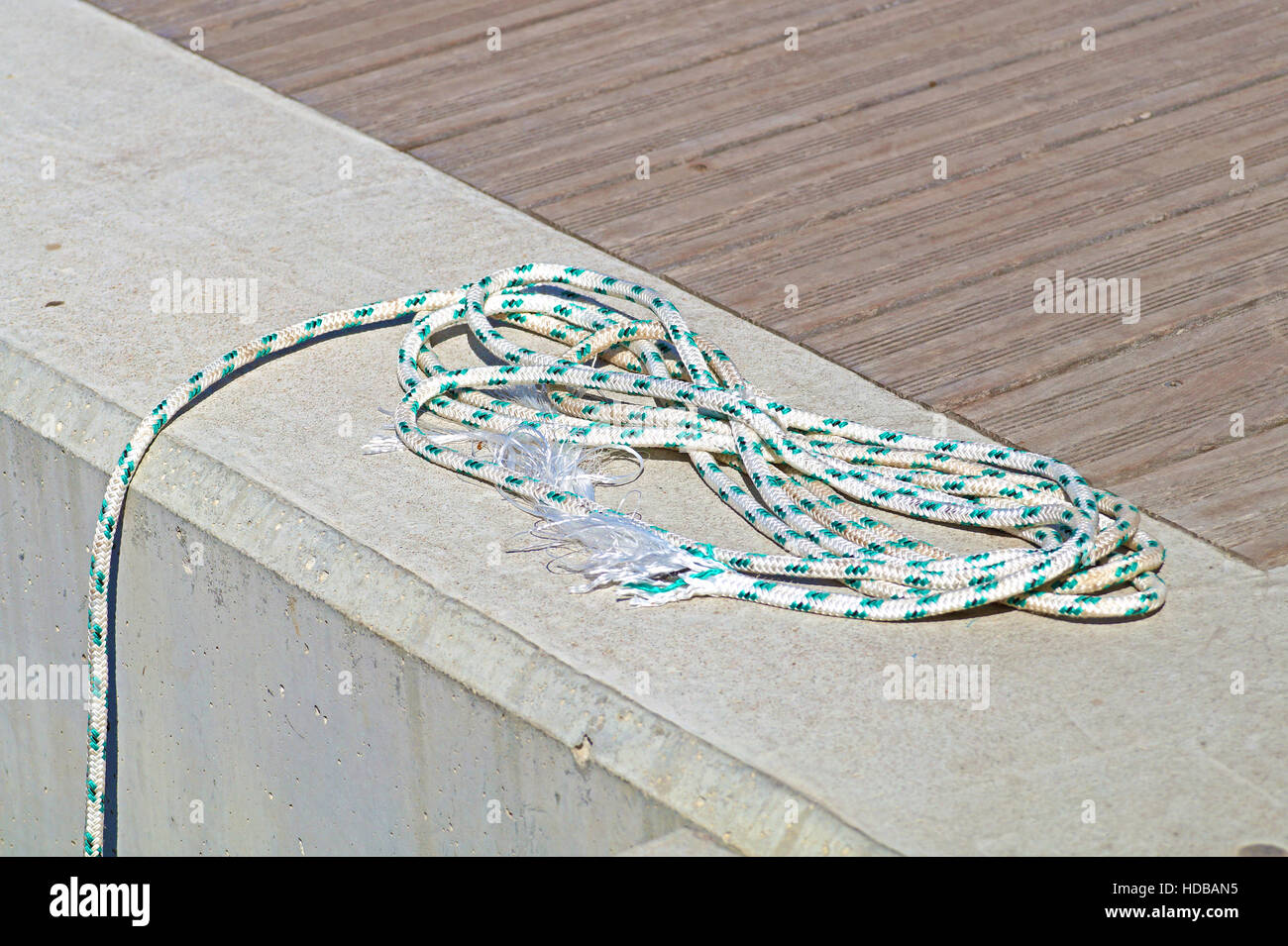 Coiled mooring line tied around cleat on a wooden dock Stock Photo - Alamy
