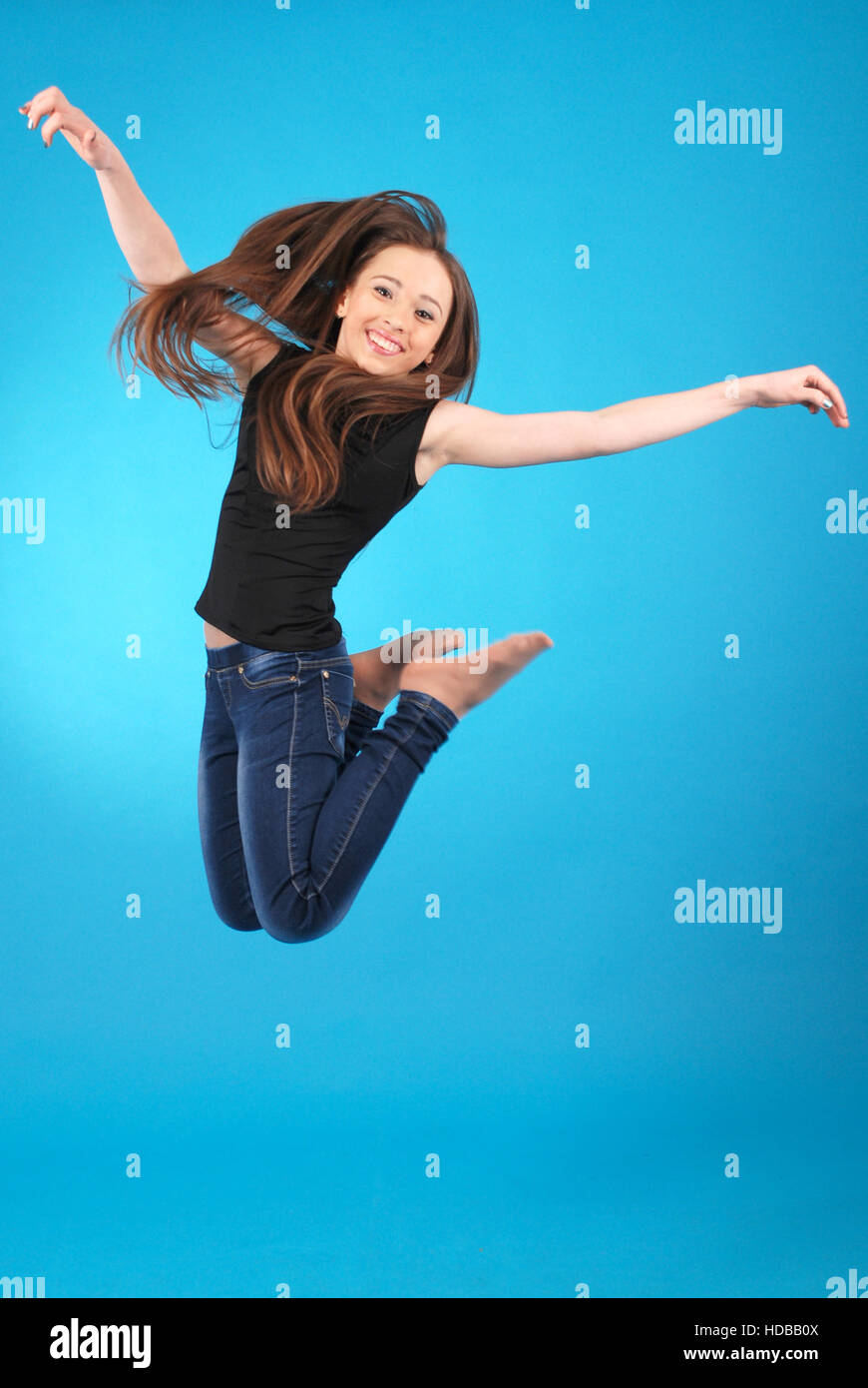 Girl jumping isolated on blue studio background Stock Photo - Alamy