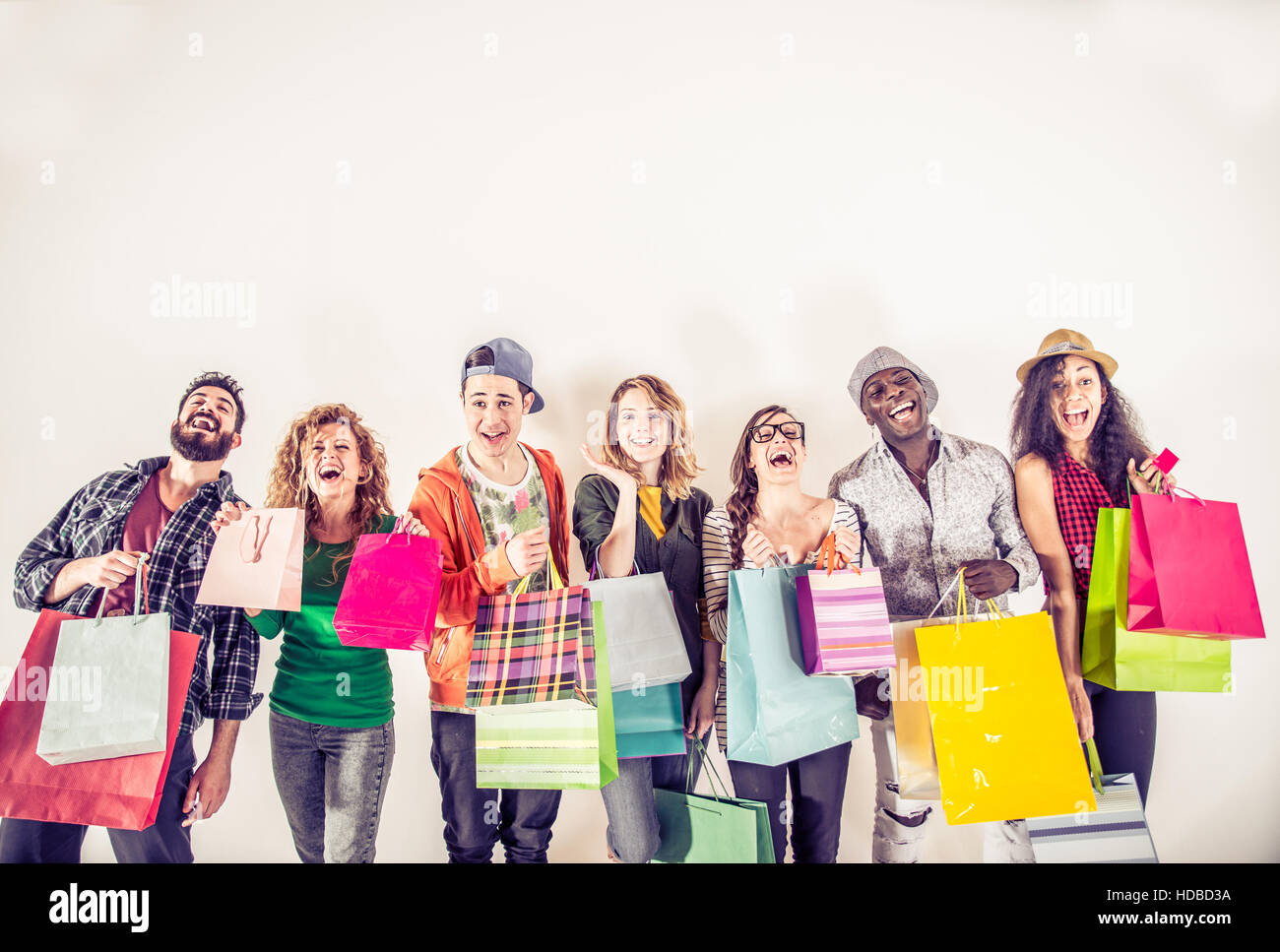 Multi-ethnic group of people holding colored shopping bags and laughing ...