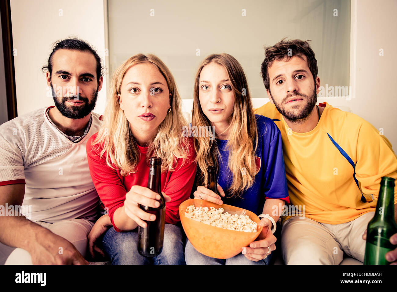 Young attractive people watching TV at home - Group of friends looking ...