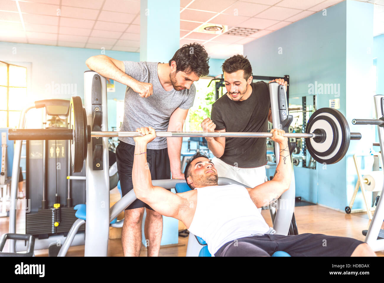 Sportive man lifting weight in a gym - Coach inciting a body builder to ...