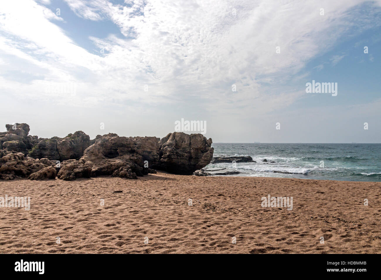 Large formation of rocks on shoreline between beach and ocean against ...