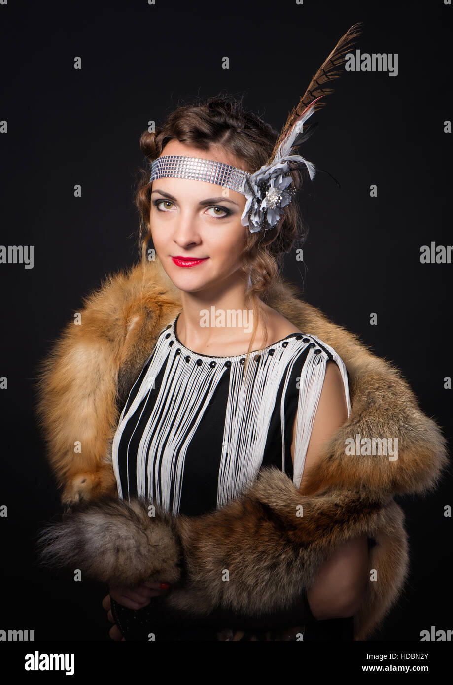 The beautiful girl with a skin of fox on shoulders and feather in ...