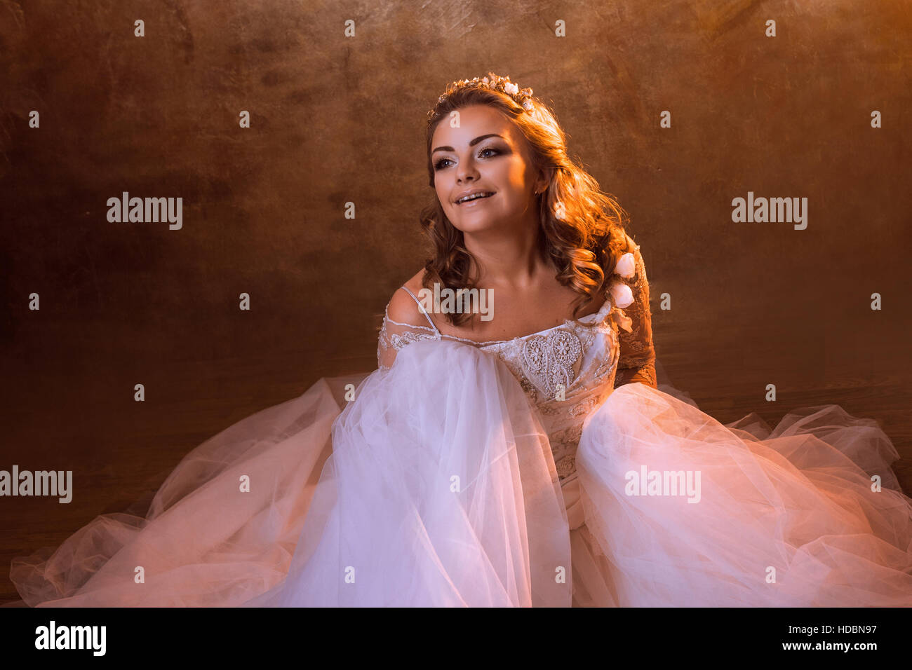 Very happy girl bride in luxurious wedding dress sitting on the floor ...