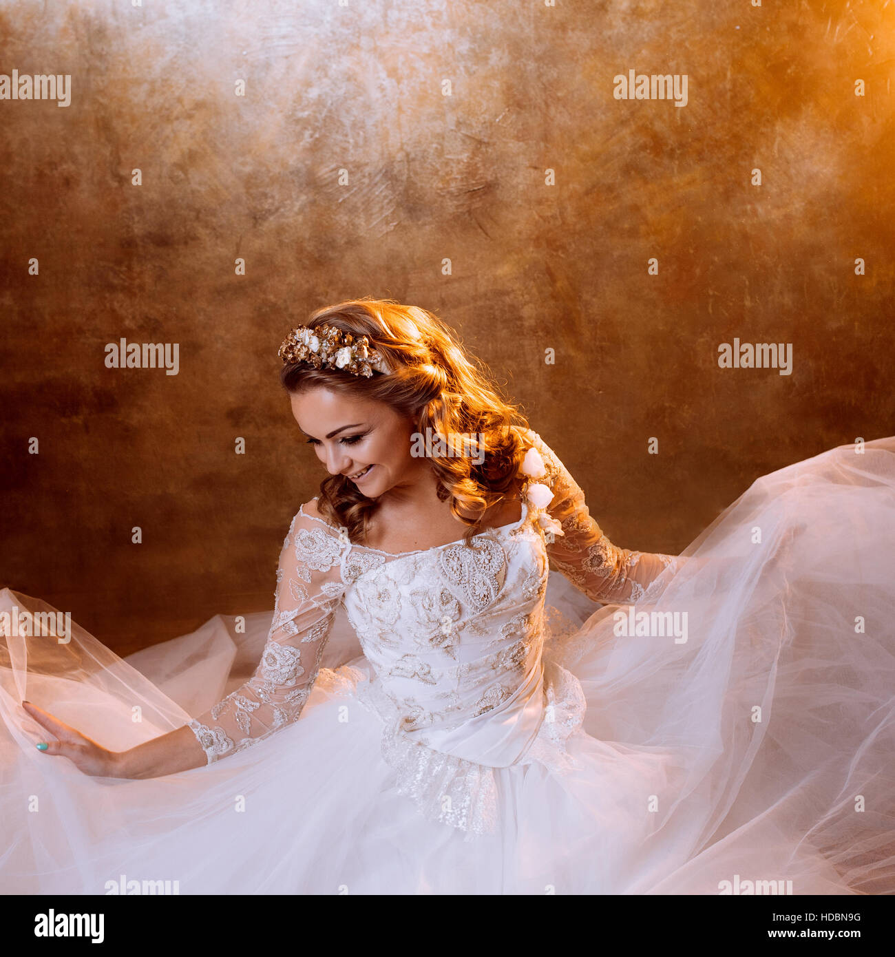 Very happy girl bride in luxurious wedding dress sitting on the floor ...