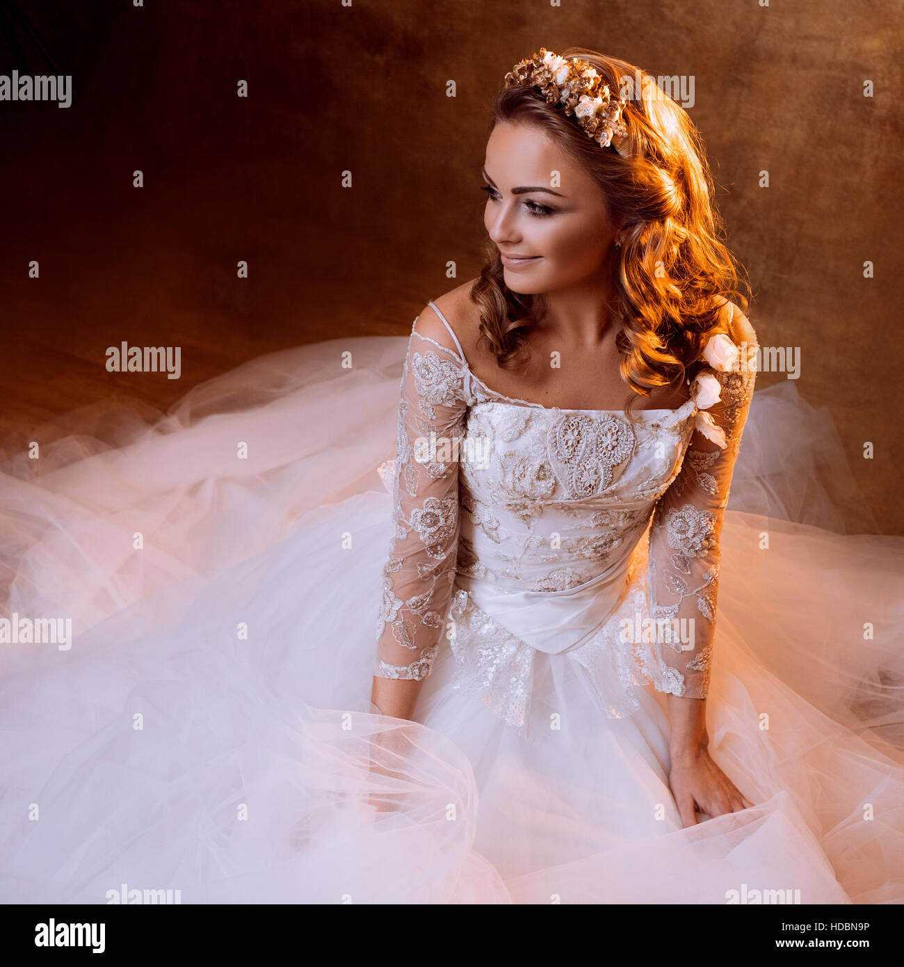 Very happy girl bride in luxurious wedding dress sitting on the floor ...