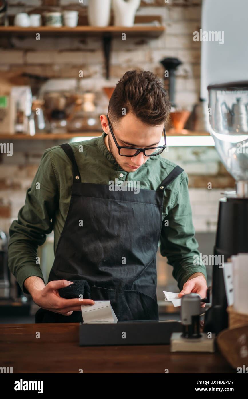 Male waiter prepares the check in coffee house. Coffee house ...