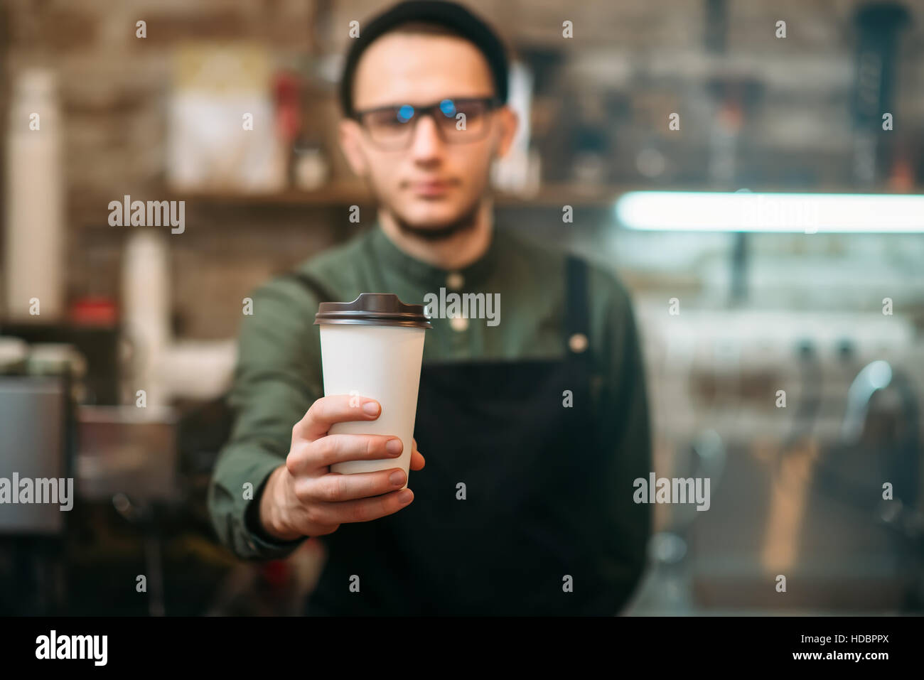 Barman in black apron stretches plastic cup of coffee in hands Stock ...