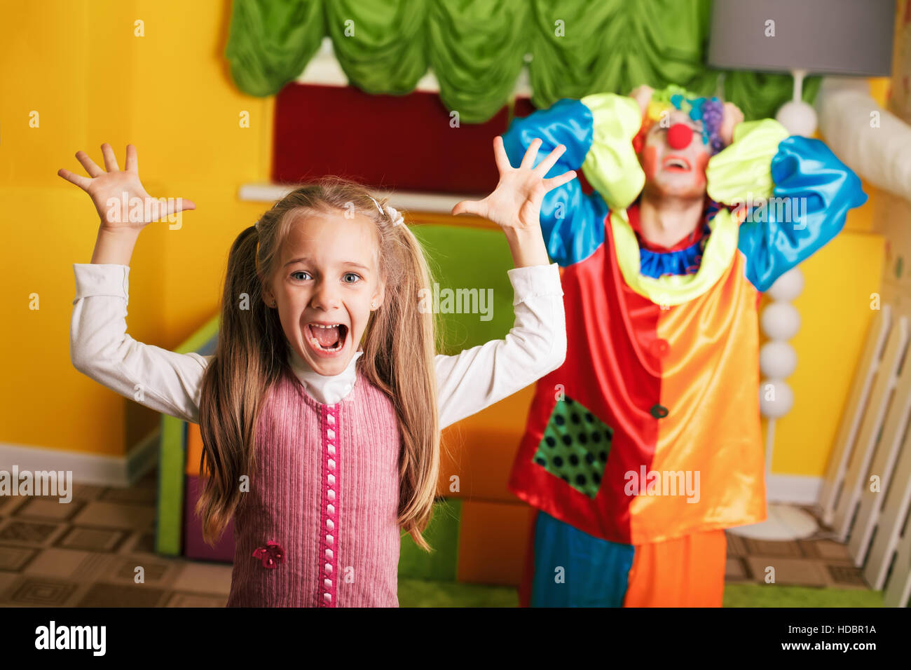 Little girl plays with upset clown Stock Photo - Alamy