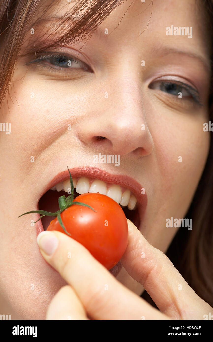 Woman biting into a cherry tomato Stock Photo - Alamy
