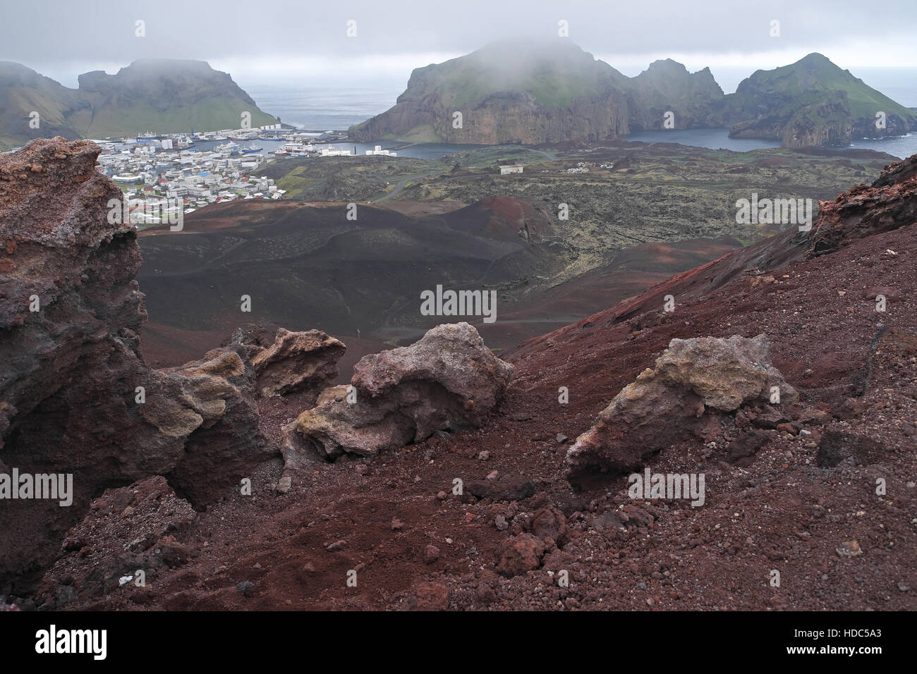 Part of Heimaey (left) seen over volcanic rocks and lava field from ...