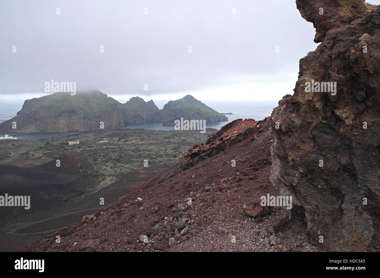 Part of Heimaey (left) seen over volcanic rocks and lava field from ...