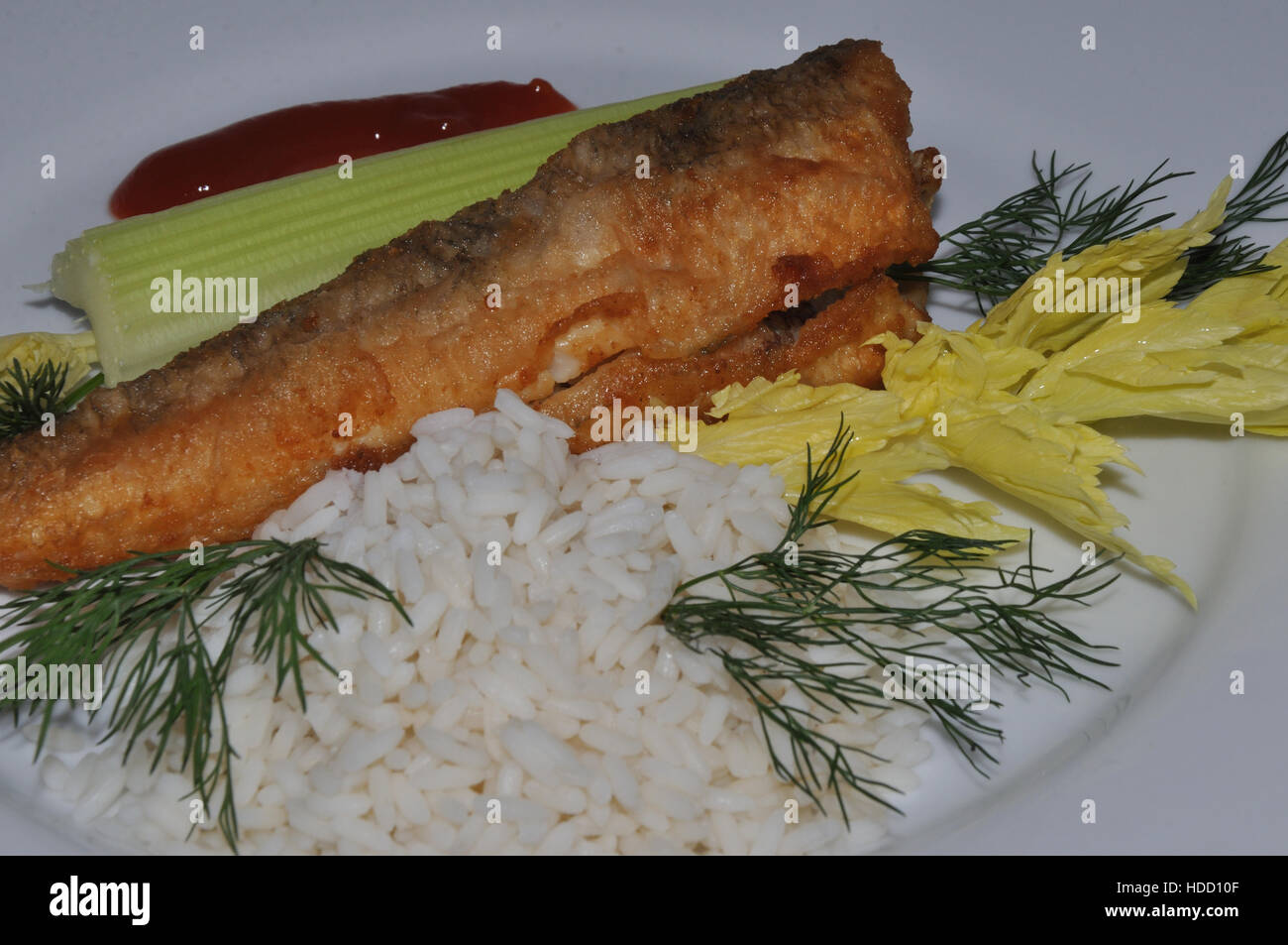 Fried fish with rice and fresh herbs Stock Photo - Alamy