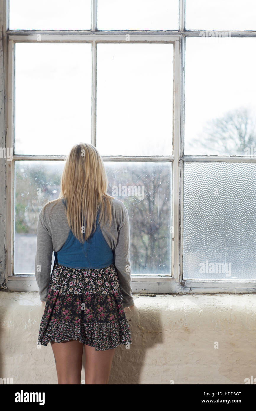 Rear view of a blond woman standing by the window Stock Photo - Alamy