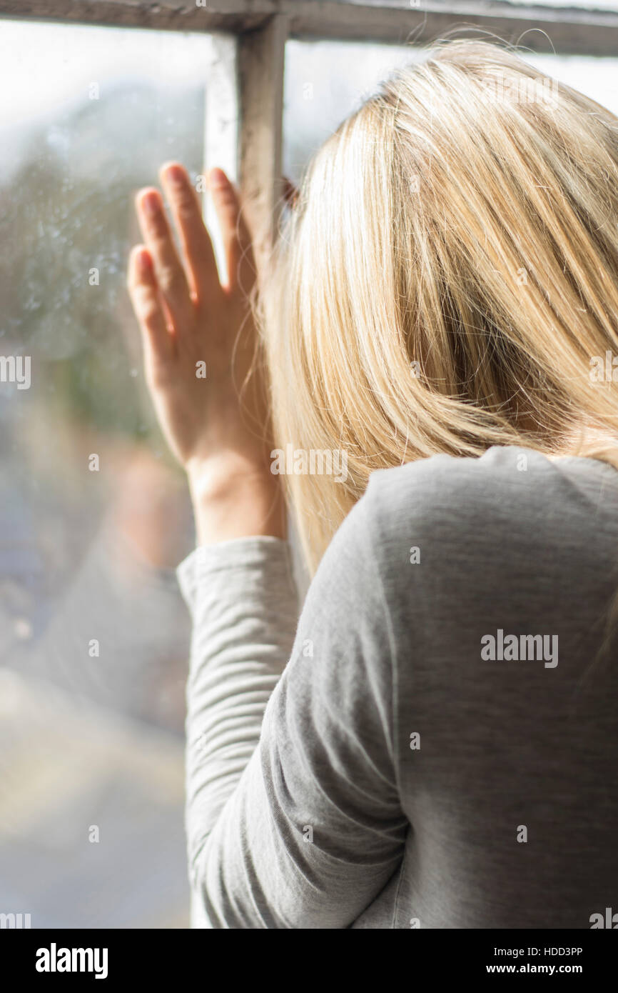 Sad woman by the window Stock Photo - Alamy