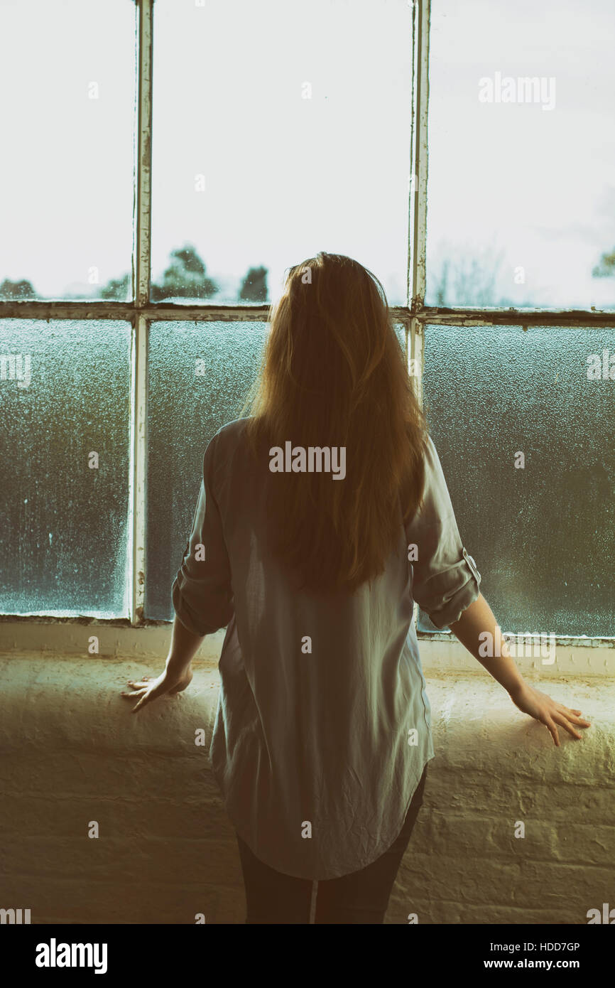 Rear view of a woman waiting by the window Stock Photo - Alamy