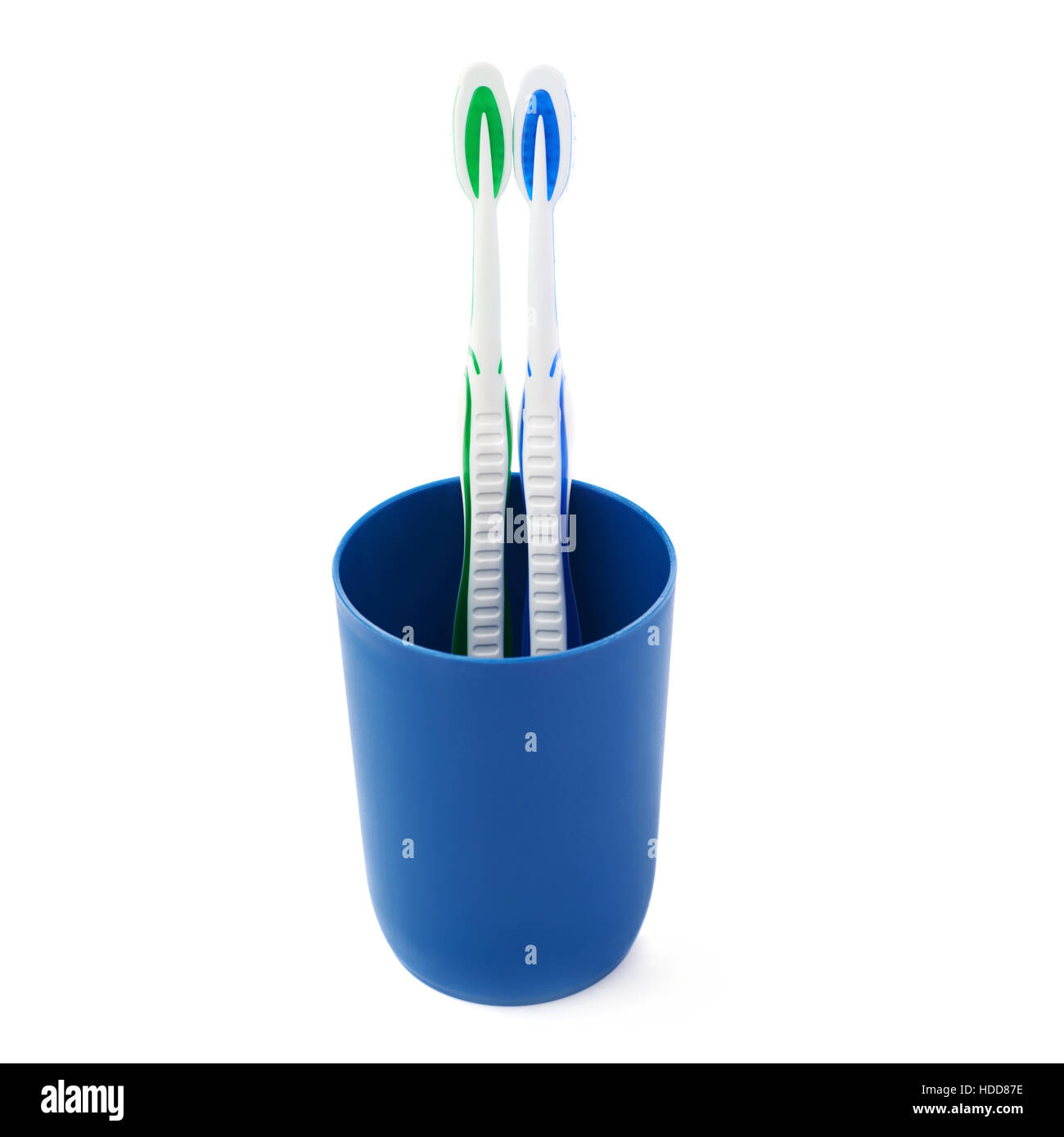 Pair of green and blue toothbrushes in blue plastic cup isolated over ...