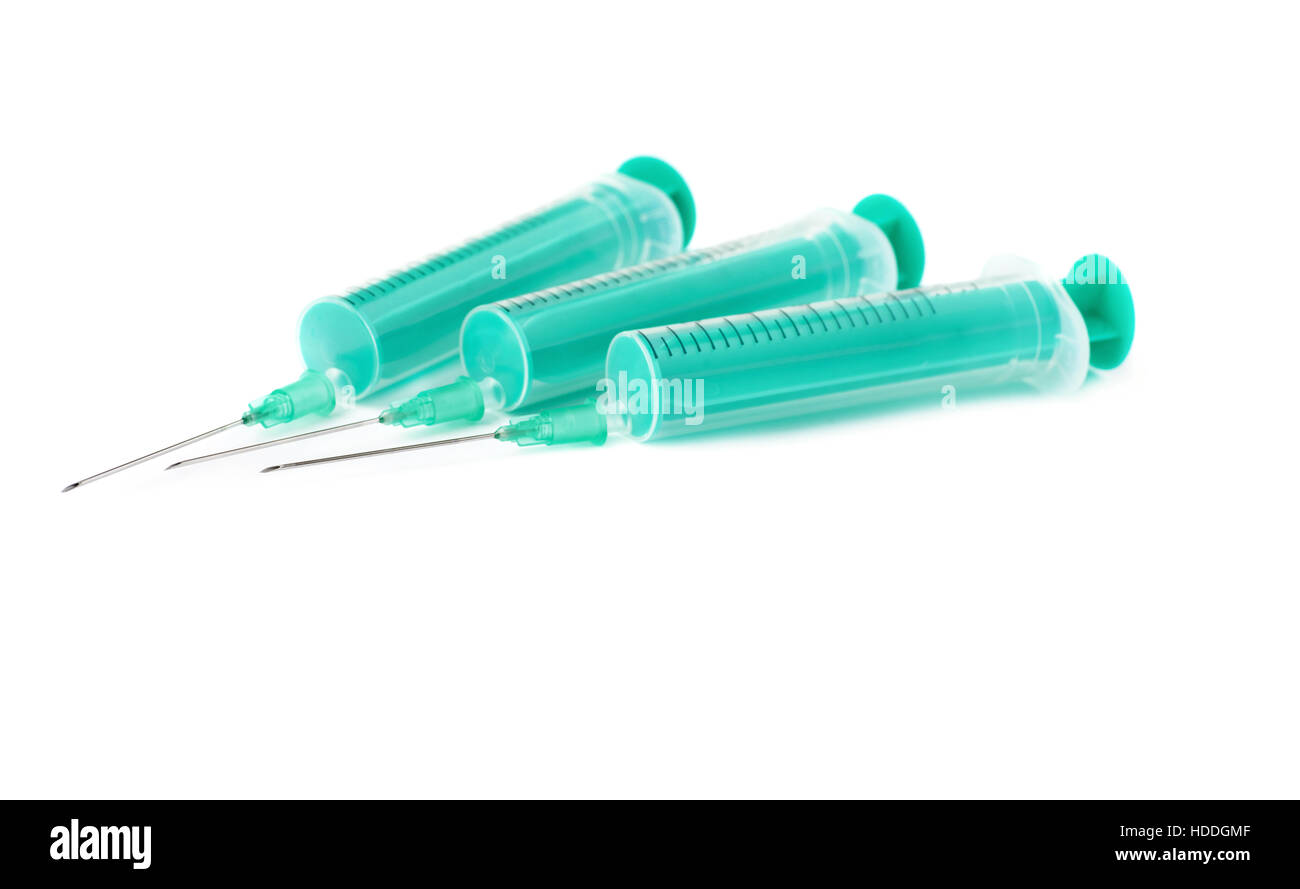 Three one-off green medical syringes with needles lying isolated over ...