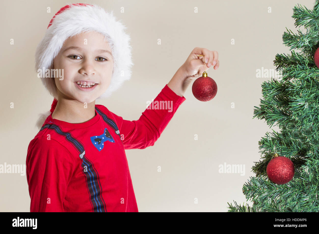 Happy boy in Santa cap decorating Christmas tree Stock Photo - Alamy