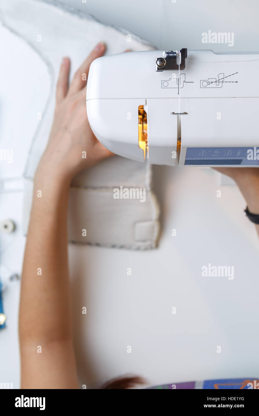 Girl tailoring fabric on sewing machine standing on table Stock Photo ...