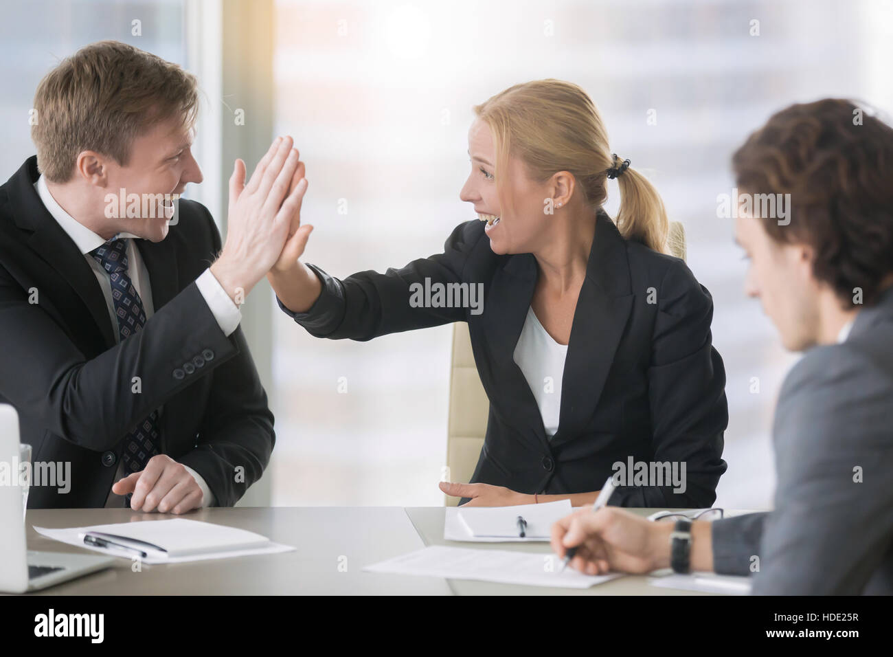 Businessman and businesswoman giving a high five Stock Photo - Alamy