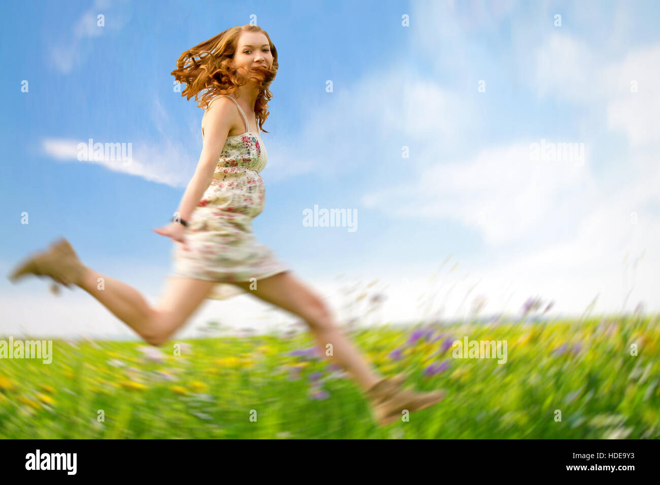 Happy girl jumping high on a flower field Stock Photo - Alamy