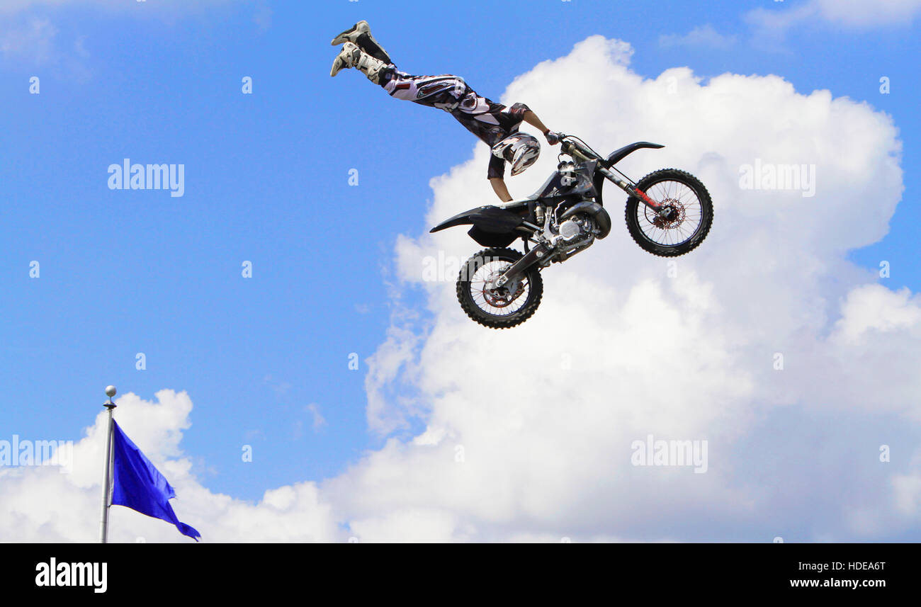 A motorcycle rider does a stunt as he flies high in the sky going over ...