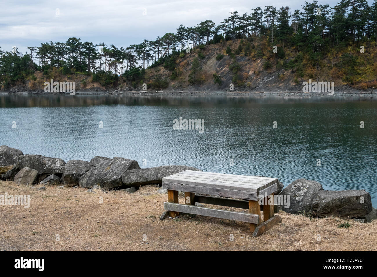 Wood bench overlooking inlet on a cloudy day Stock Photo - Alamy