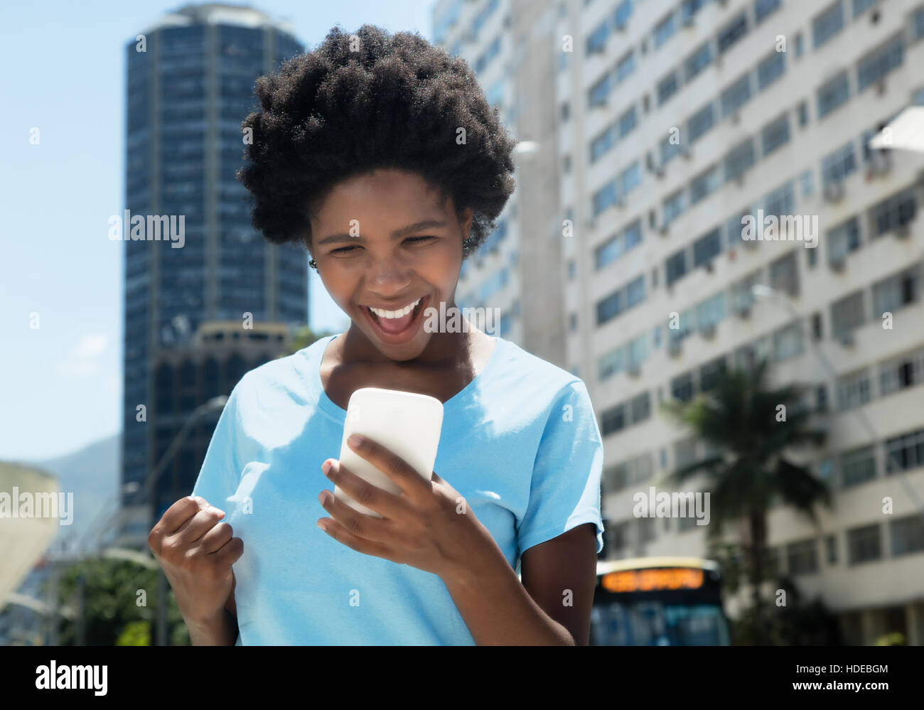 Cheering african american girl with cell phone outdoor in the city in ...