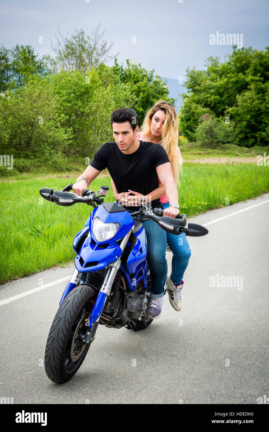 Handsome young man riding motorcycle with woman as passenger Stock ...