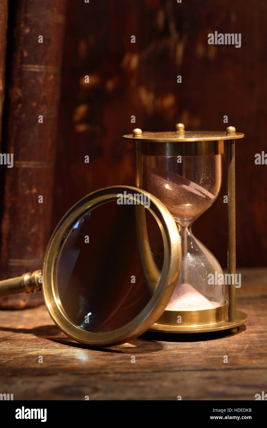 Still life with vintage hourglass near magnifying glass Stock Photo - Alamy