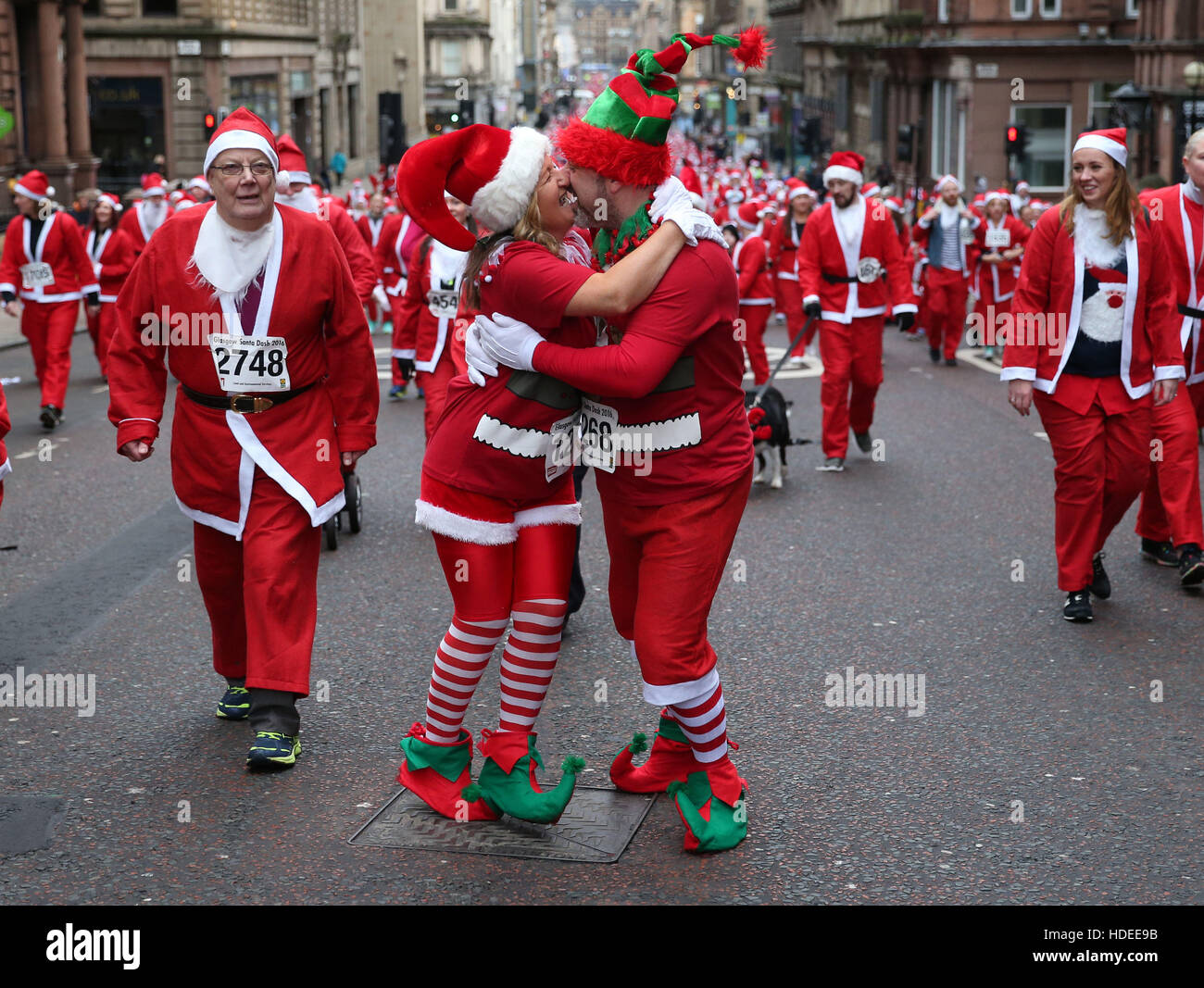 A couple embrace as runners in Santa costumes take part in the Glasgow ...