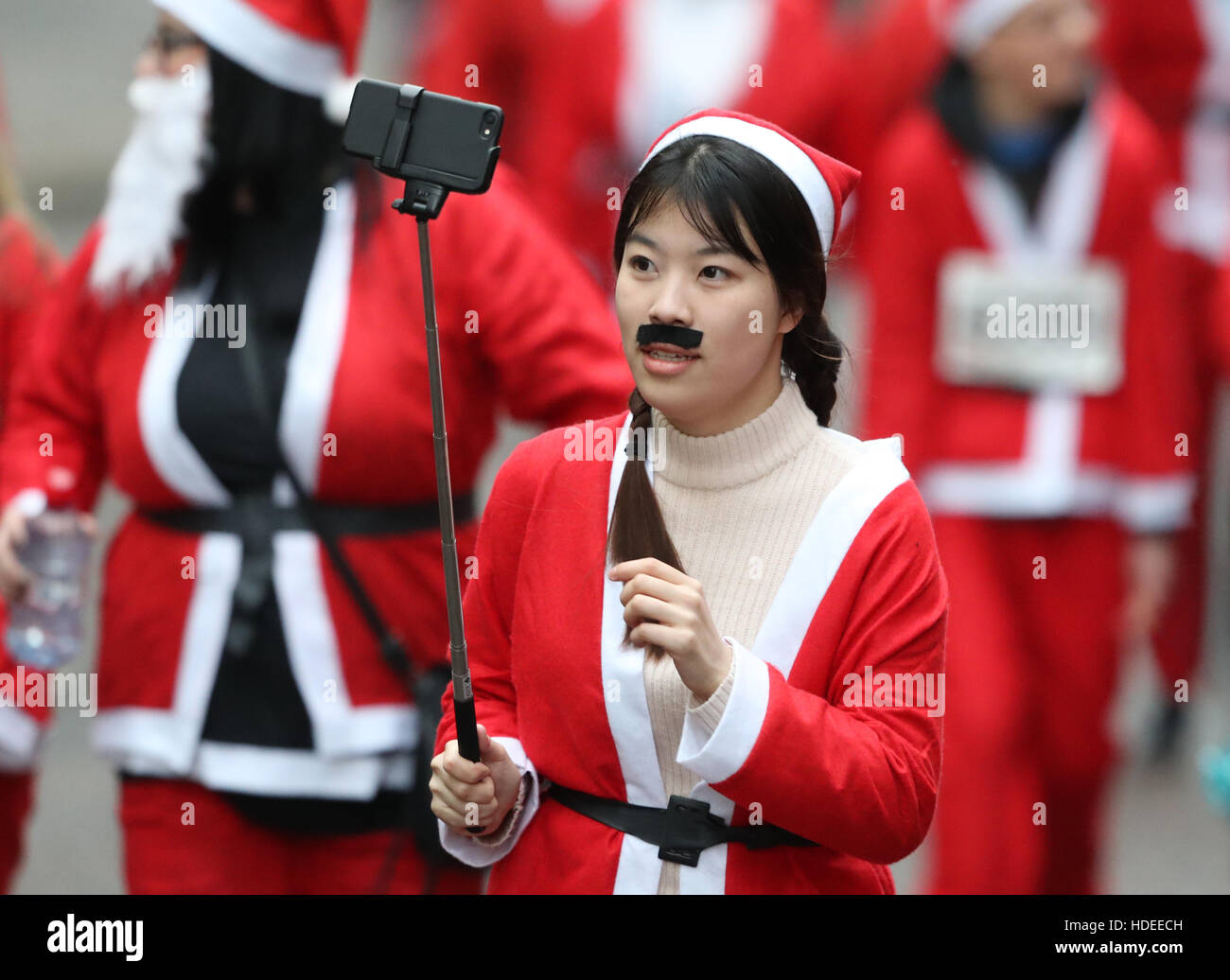 A runner in a Santa costume takes a selfie as she takes part in the ...