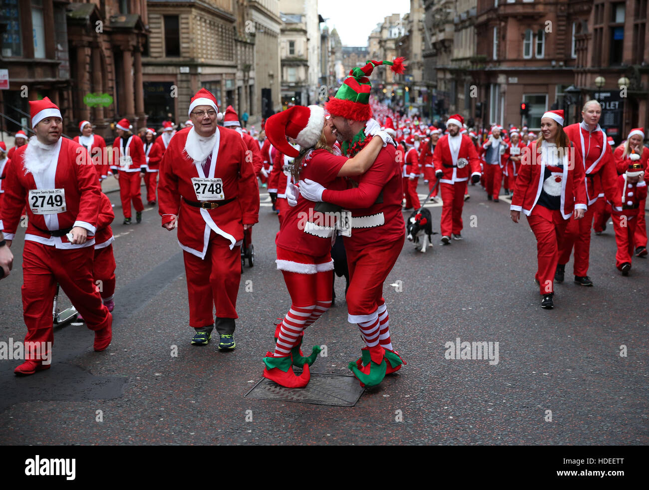 A couple embrace as runners in Santa costumes take part in the Glasgow ...