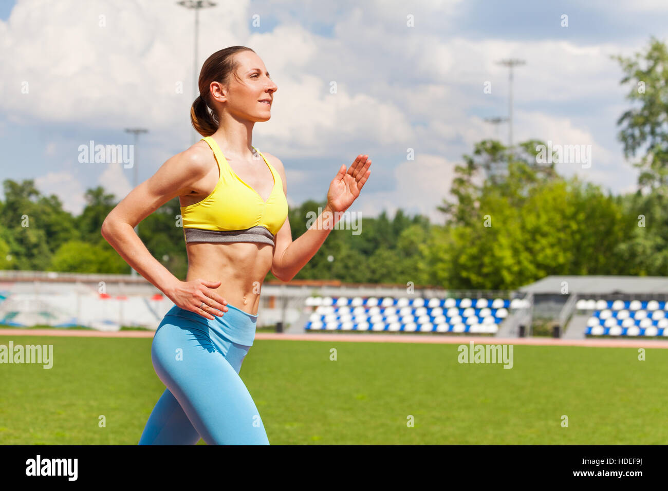 Young woman running at stadium in summer Stock Photo - Alamy