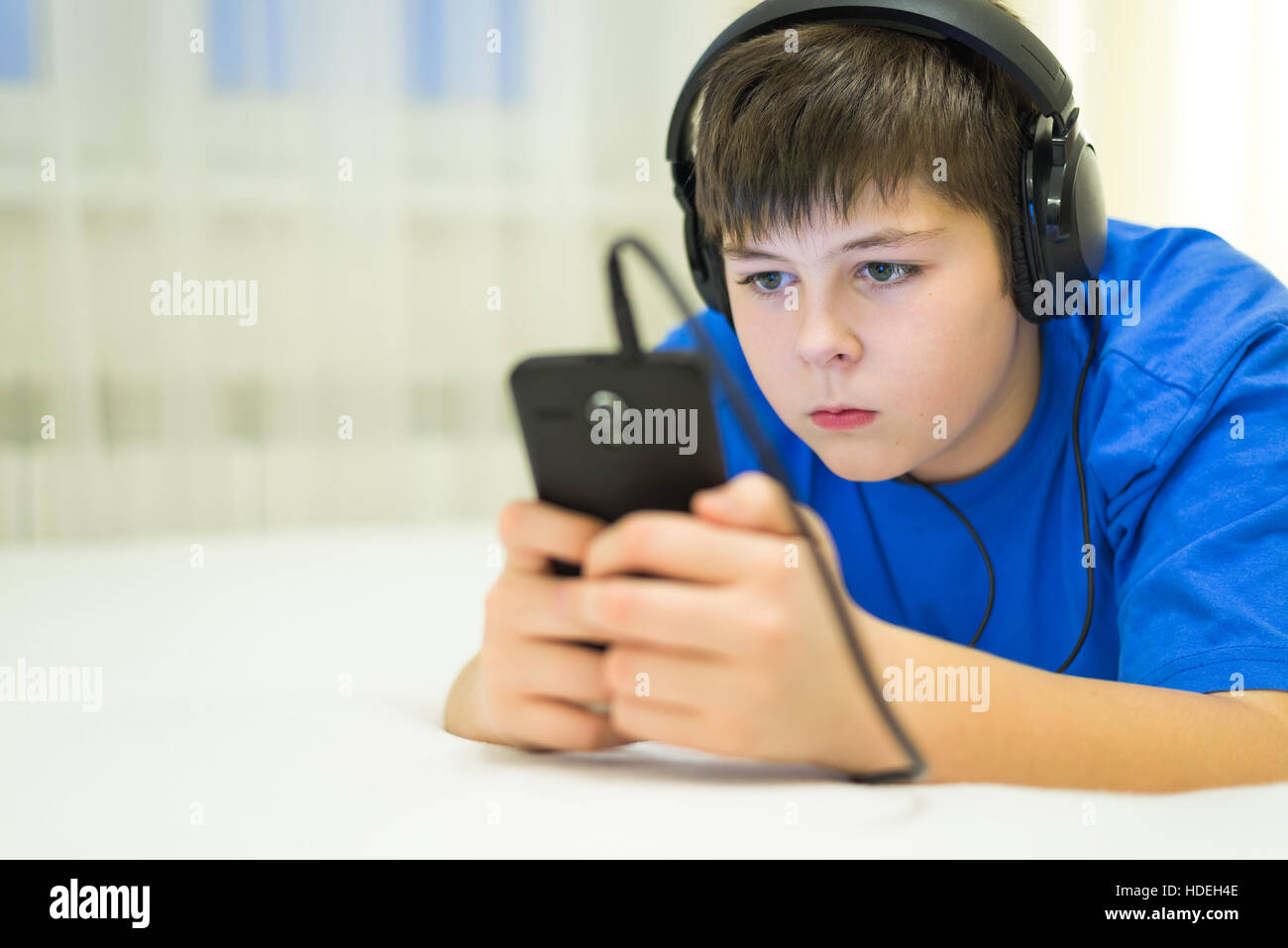 Teen using cell phone with headphones Stock Photo - Alamy