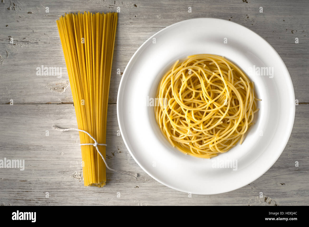 Raw and cooked spaghetti on the white wooden table top view Stock Photo ...