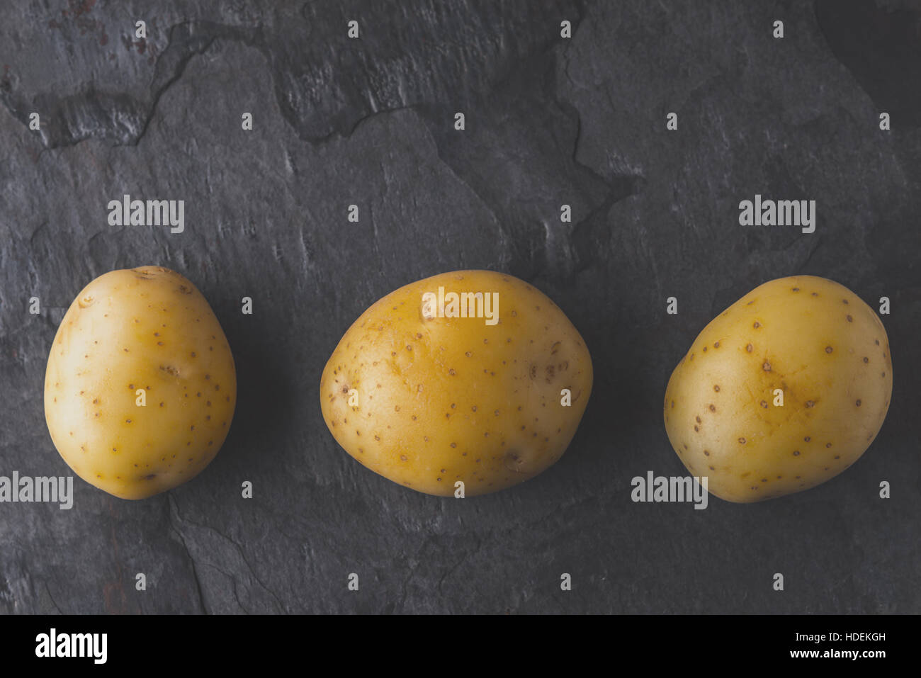 Potatoes on the dark stone table top view Stock Photo - Alamy
