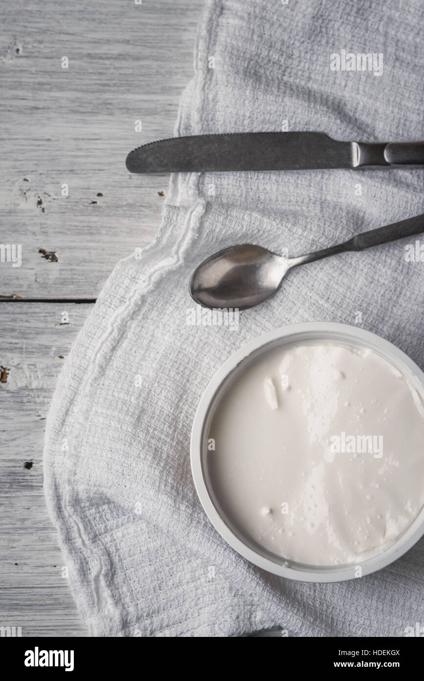 Ricotta with cutlery and napkin on the white wooden table vertical ...