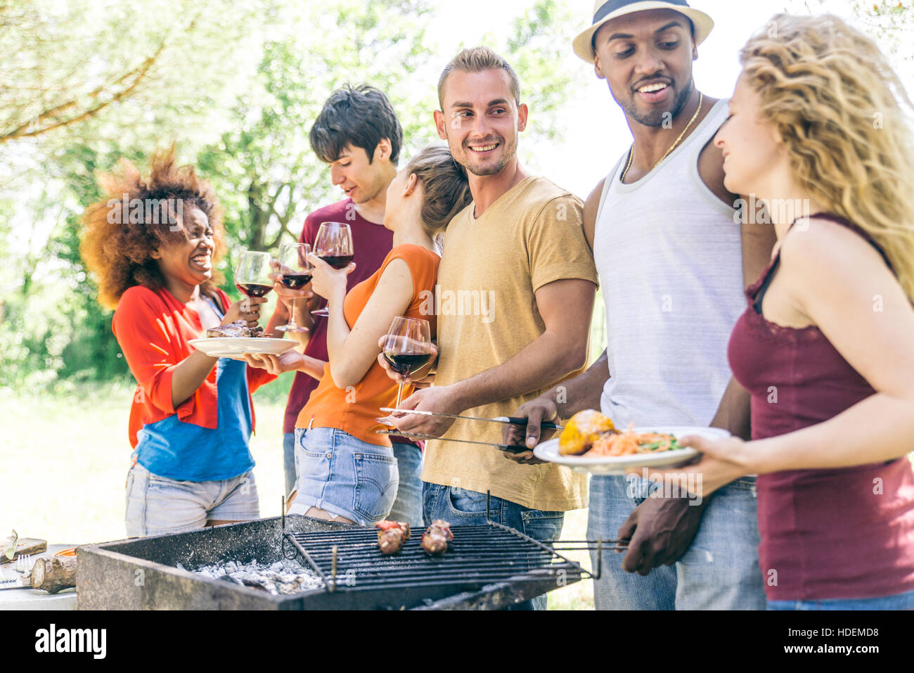 Multi-ethnic group of friends talking and having fun at a barbeque ...