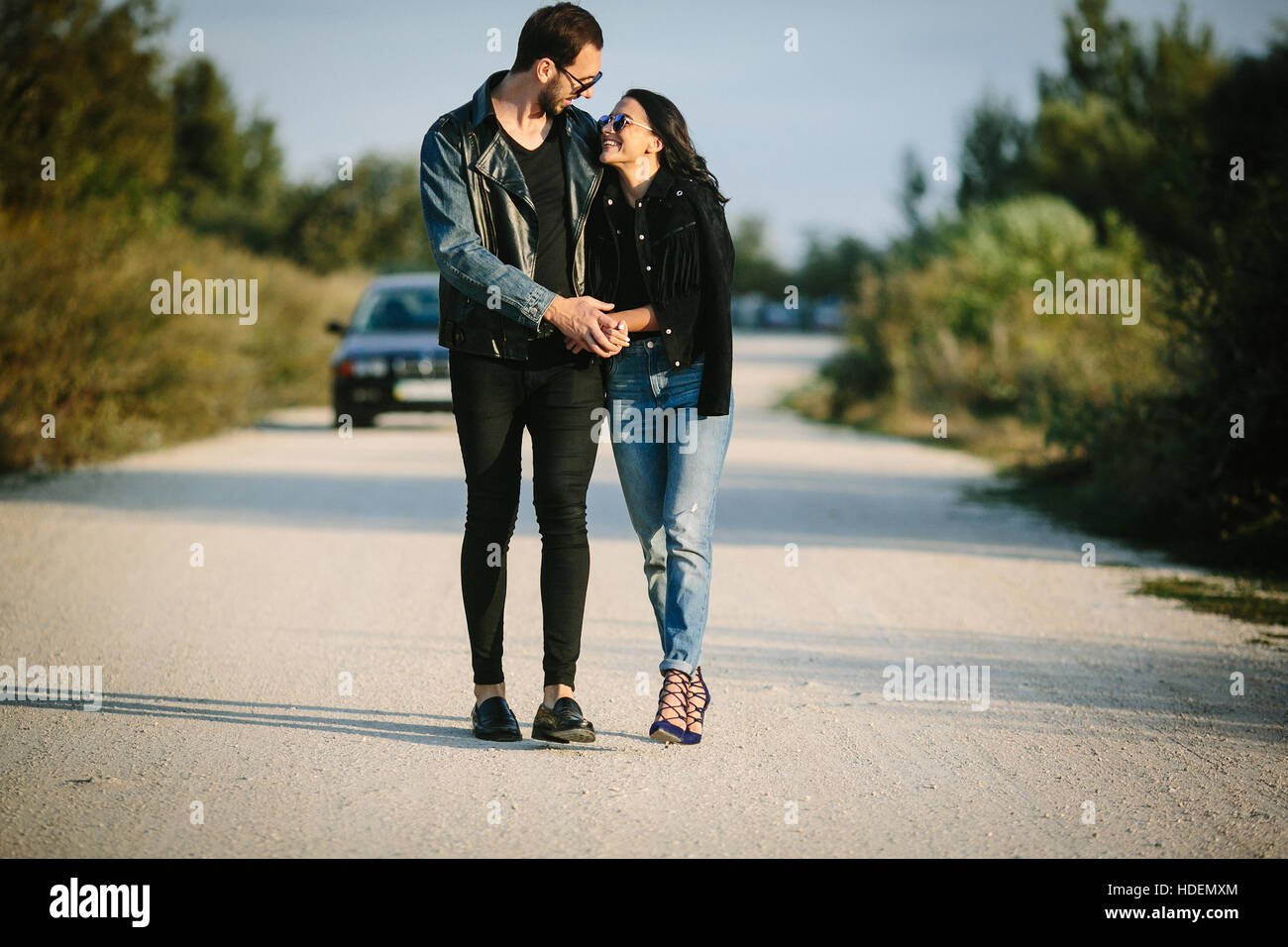 Young happy romantic couple walking along road Stock Photo - Alamy