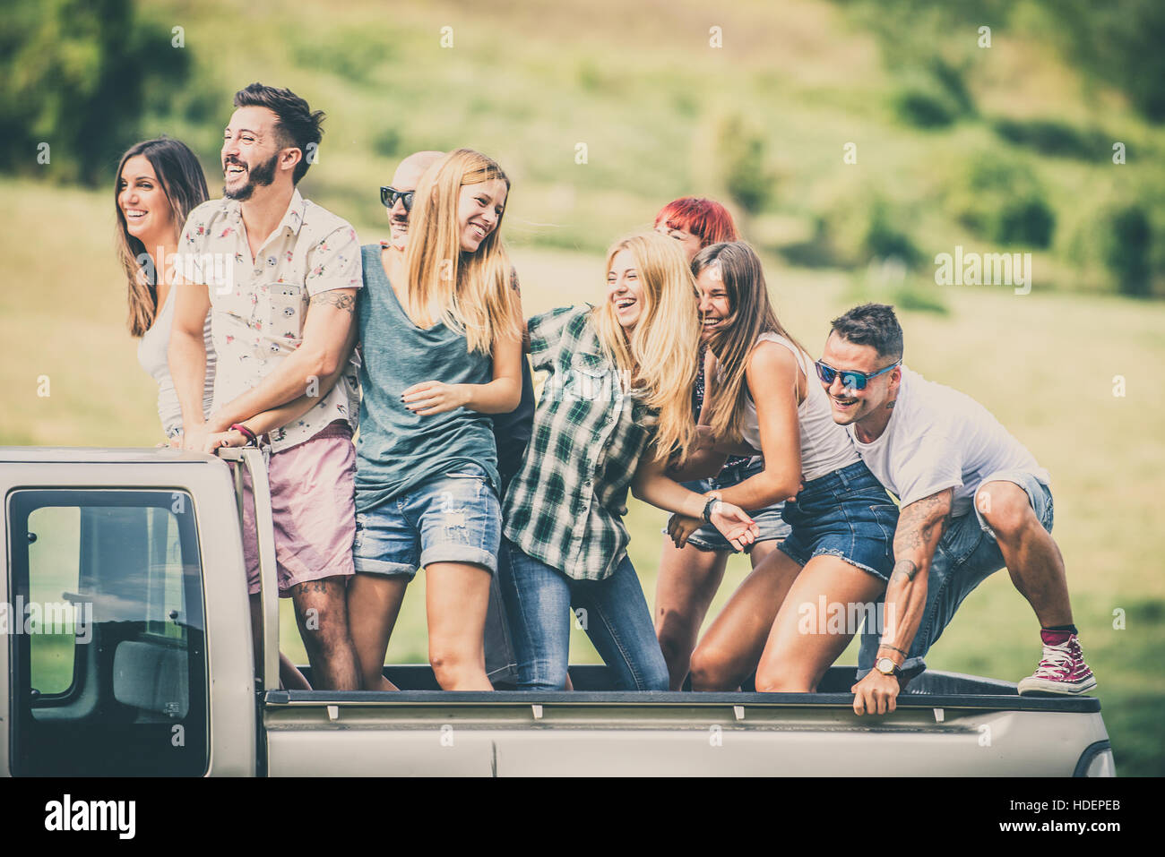 Group of friends driving on the back of pick-up car and having fun ...